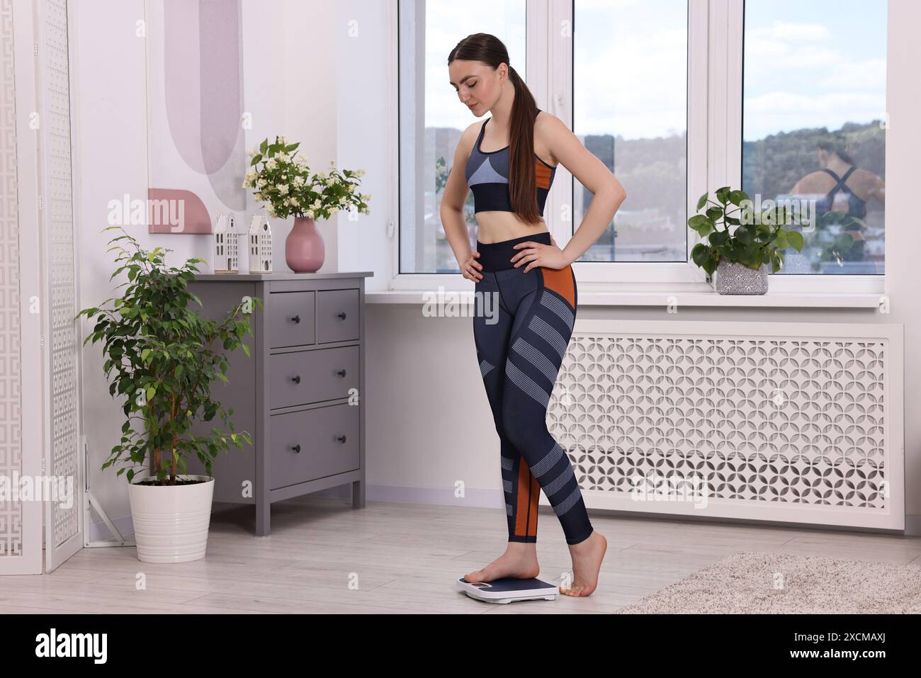 Woman stepping on floor scale at home Stock Photo - Alamy