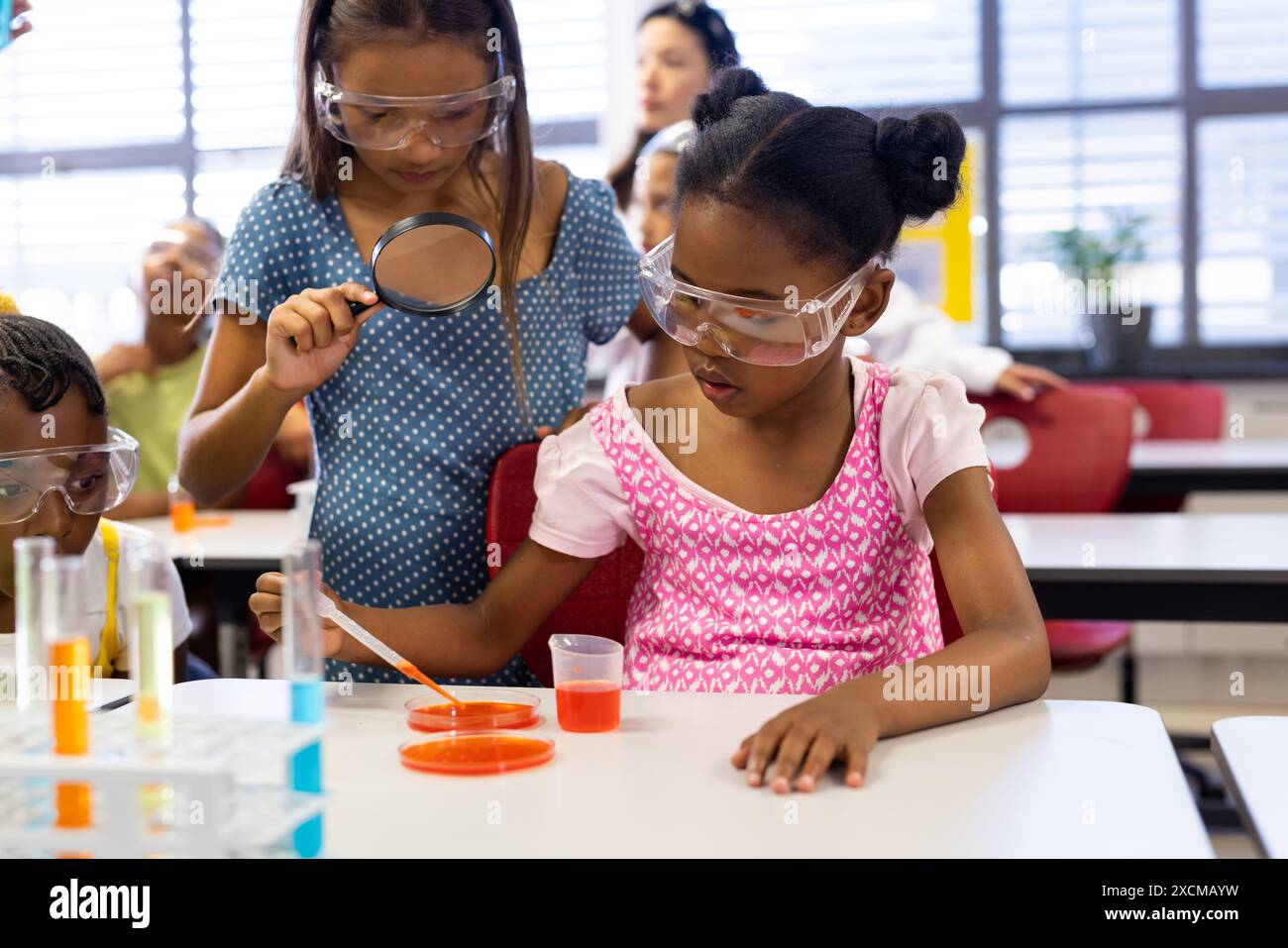 Diverse female teacher and schoolgirls with chemistry items and liquids ...