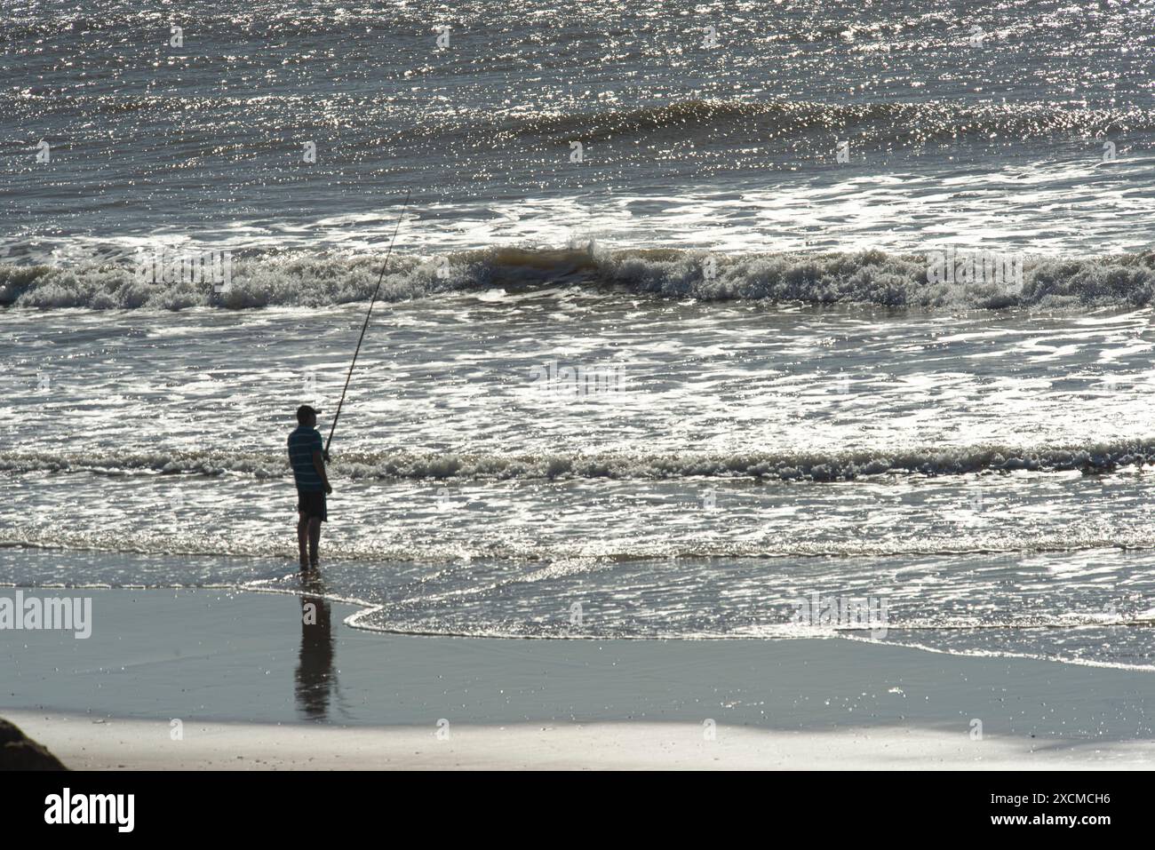 Fisherman fishing on the beach Stock Photo - Alamy