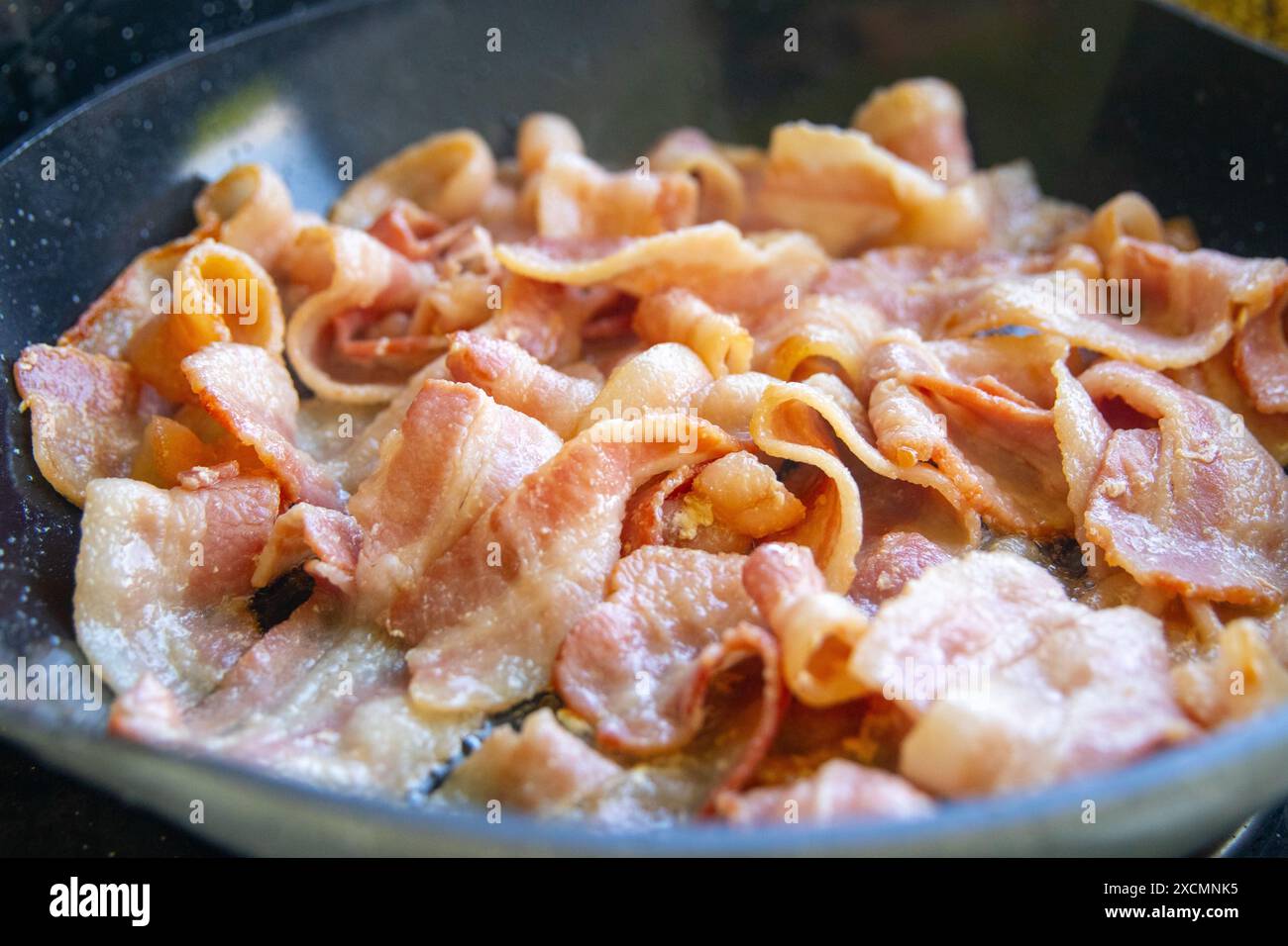 Bacon sizzling in a pan Stock Photo - Alamy