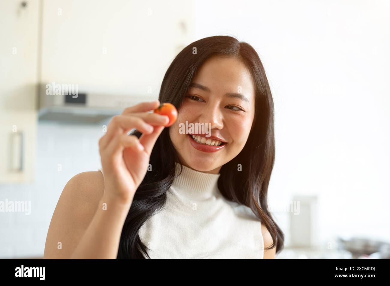 A beautiful, attractive young Asian woman enjoying cooking in the ...