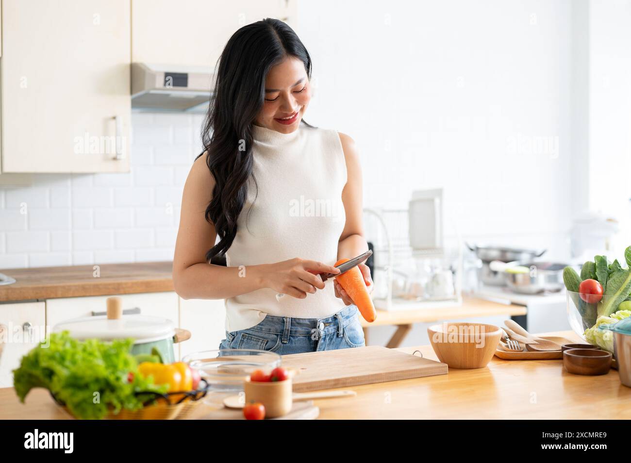An attractive, charming Asian woman cooking in the kitchen, peeling a ...
