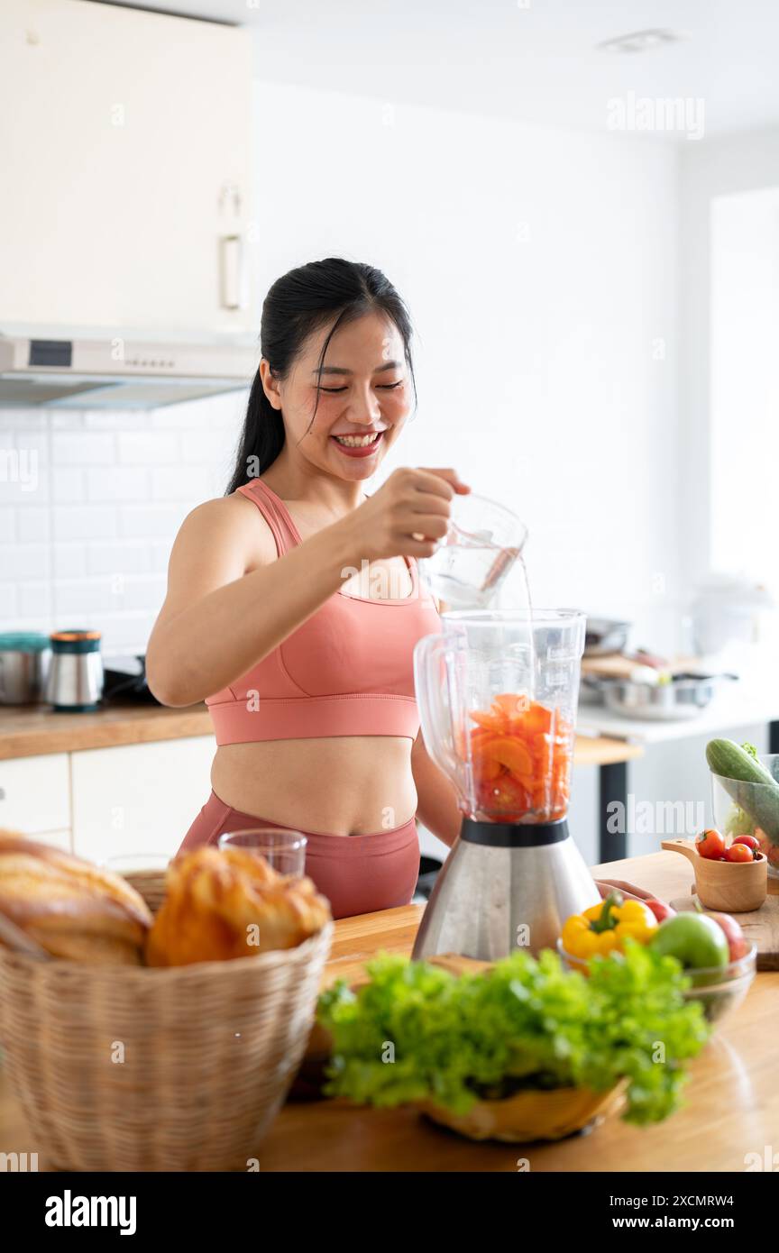 An attractive, slim, and healthy Asian woman in sportswear pouring ...