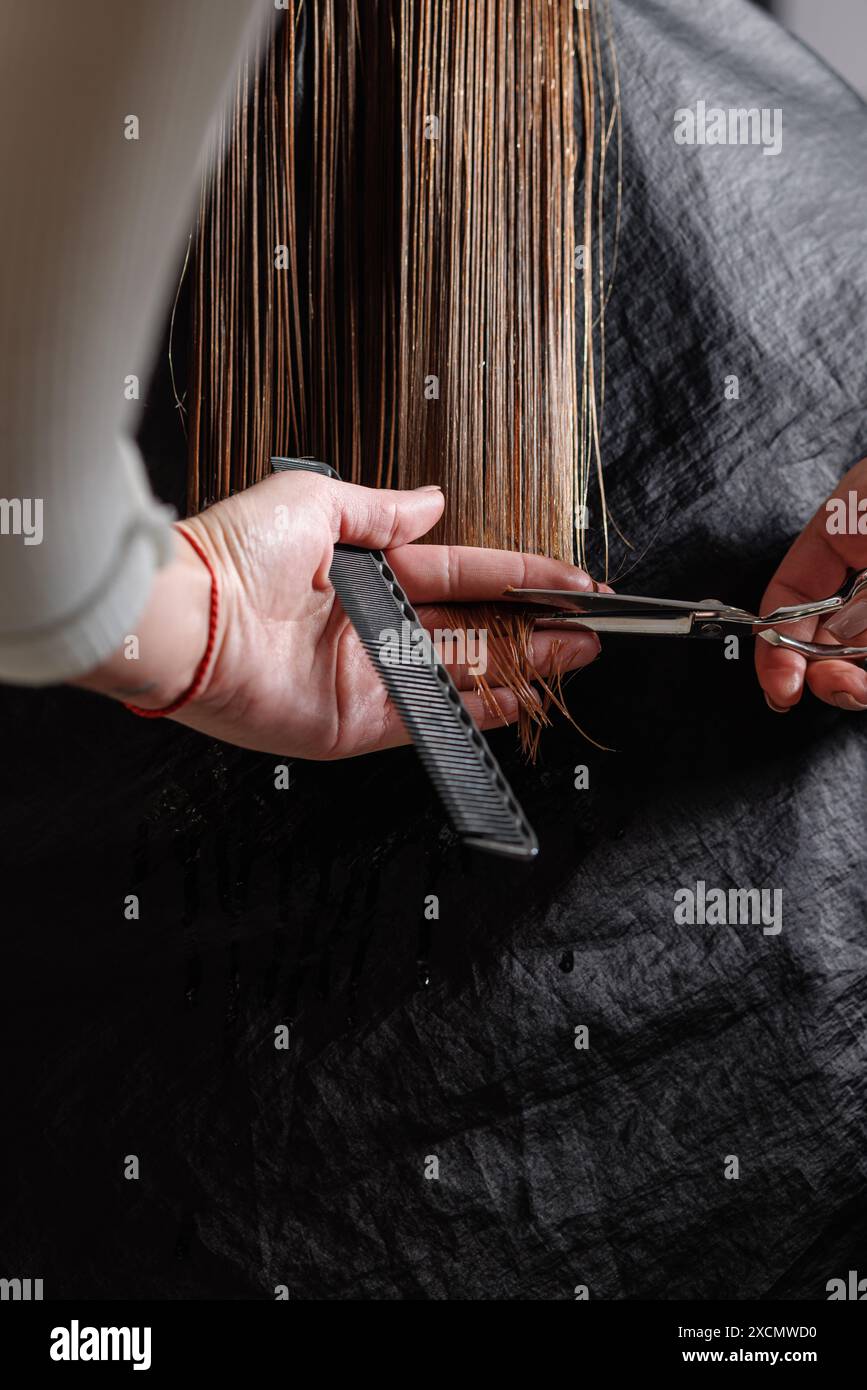 hairdresser makes a haircut to a woman in the salon. The hairdresser ...