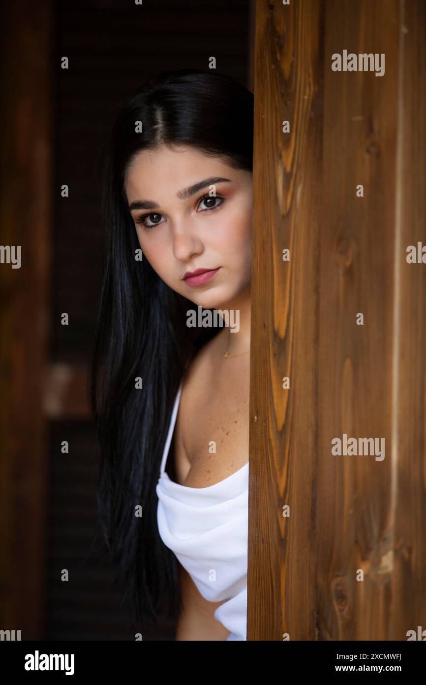 Woman standing behind door looking away Stock Photo - Alamy