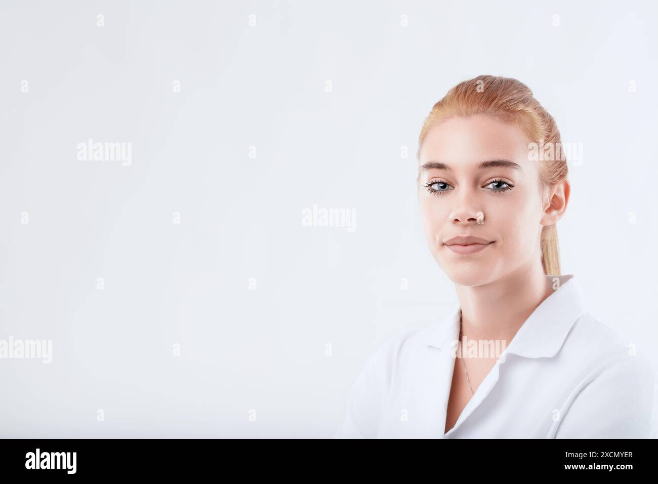 Portrait of a young doctor woman wearing a white coat, posing in front ...