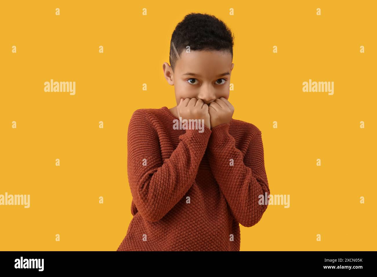 Scared little African-American boy on yellow background Stock Photo - Alamy
