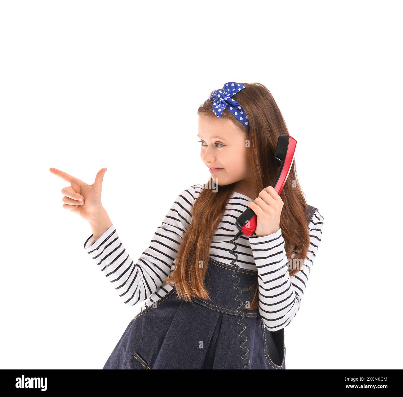 Little girl with phone receiver pointing at something on white ...