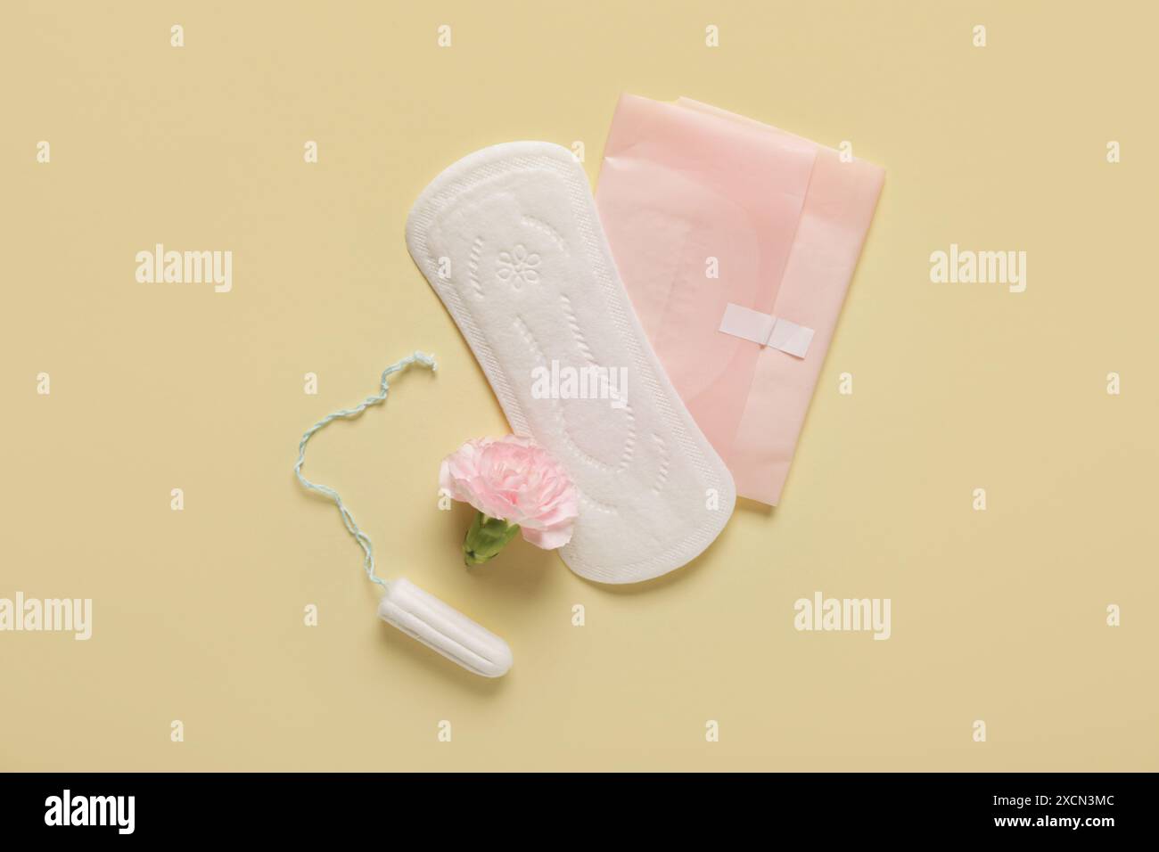 Menstrual pads with tampon and carnation flower on yellow background ...