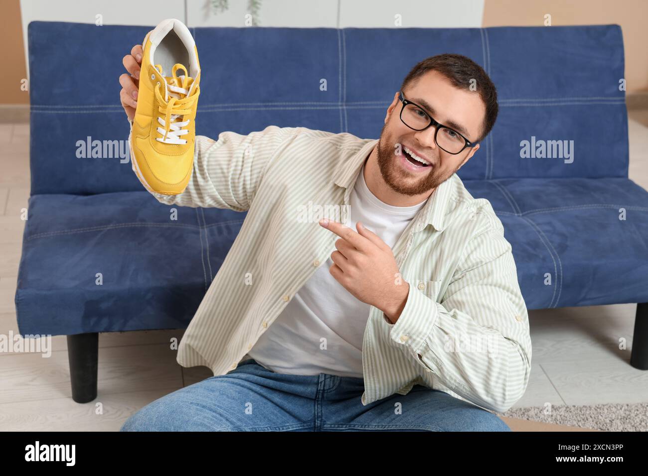 Happy young man pointing at stylish sneaker at home Stock Photo - Alamy