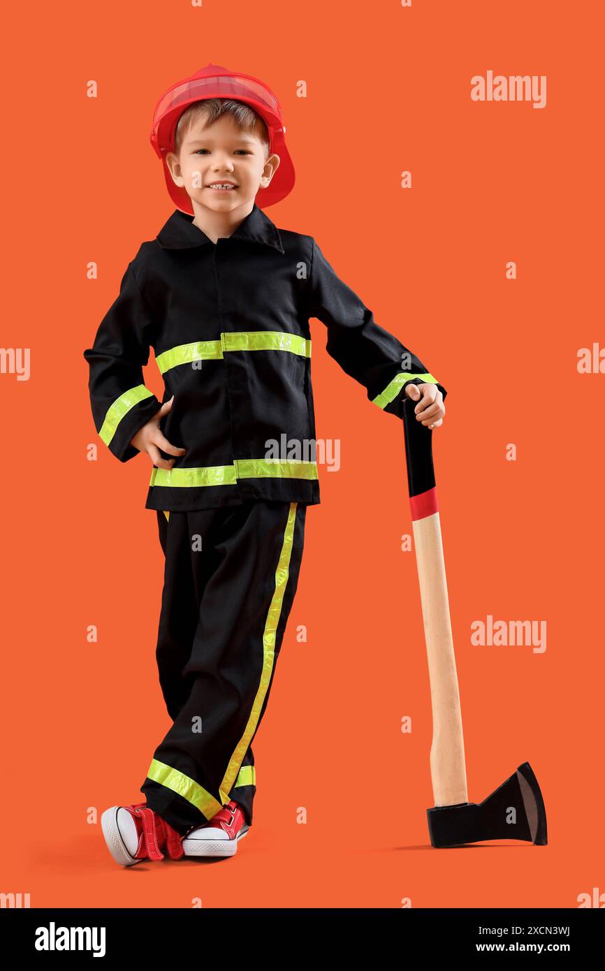 Cute little firefighter with axe on orange background Stock Photo - Alamy