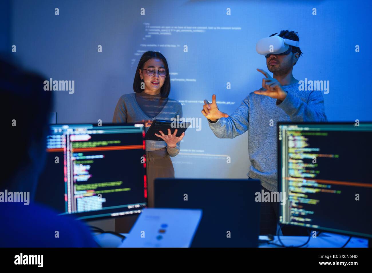 developer uses a VR headset to interact with projected interface designs, while colleagues ...
