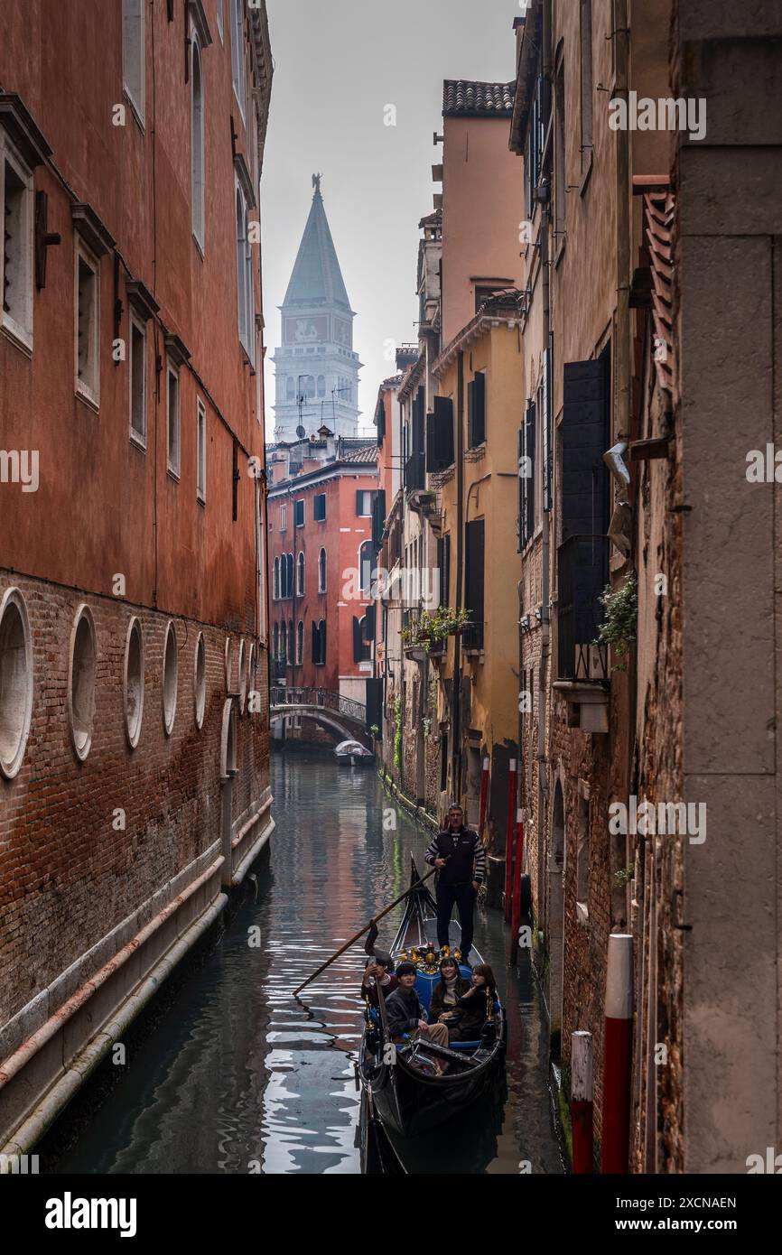 Narrow Canal in city of Venice with Asian tourists in gondola ...
