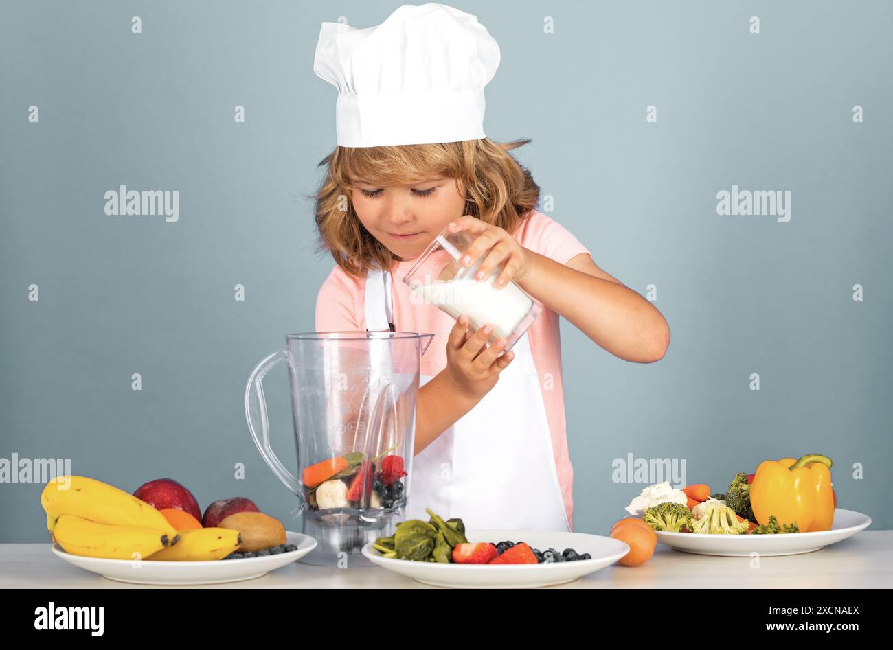 Portrait of chef child in cook hat make milk shake smoothie. Cooking at ...