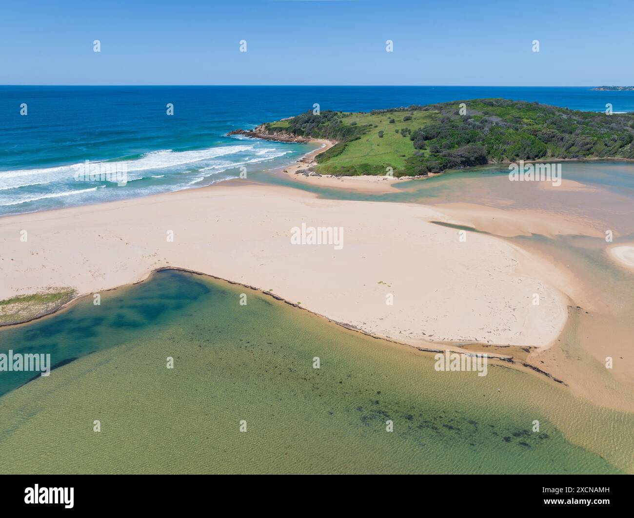 Aerial view of a coastal river flowing around sand bars and out to the ...