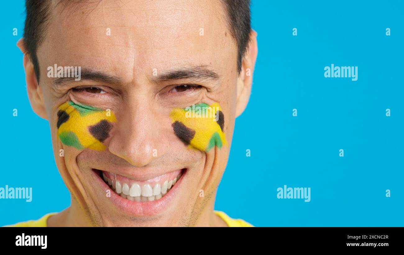 Man with a jamaican flag painted on the face smiling Stock Photo - Alamy