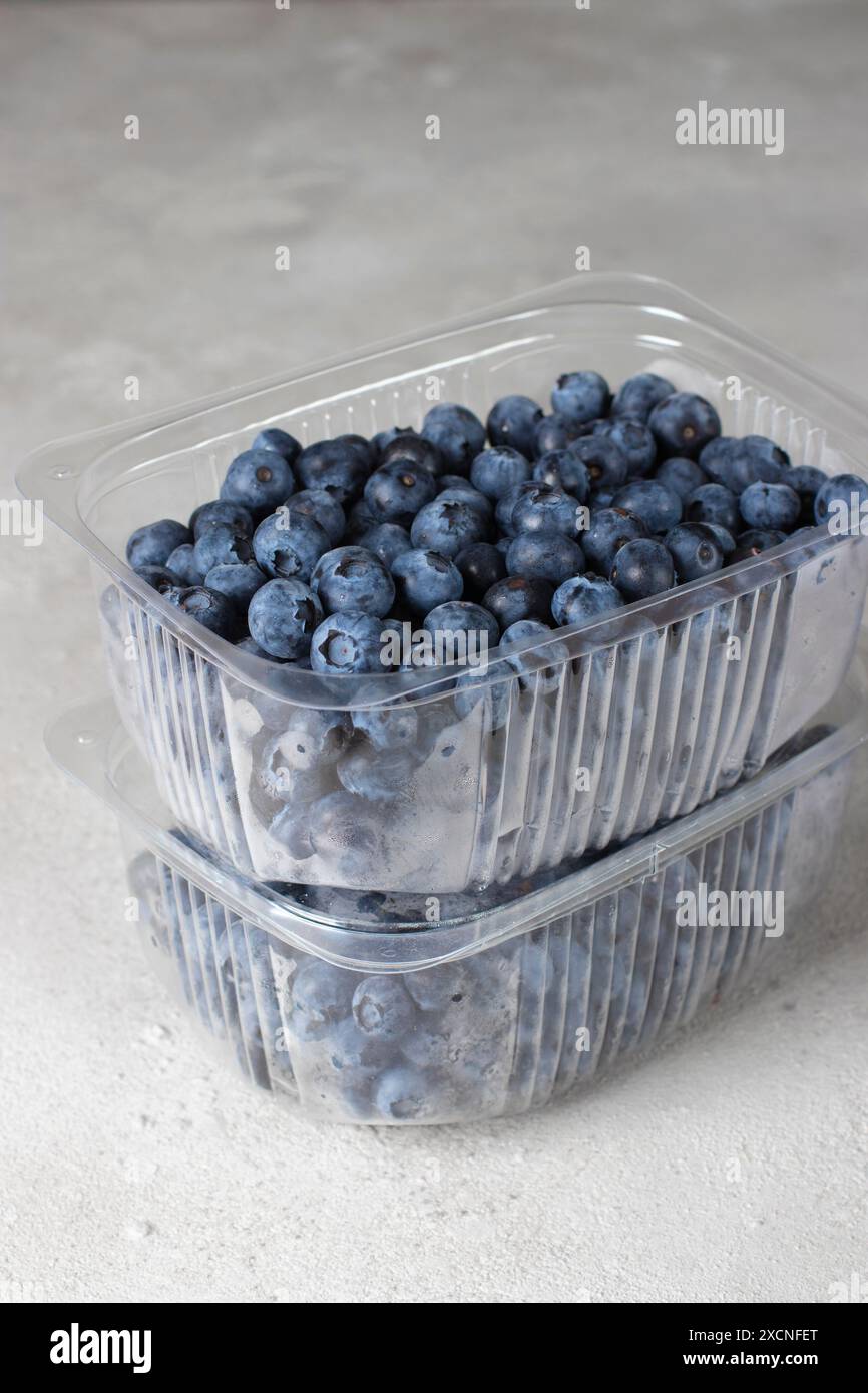 Fresh blueberries in plastic containers on gray background, preparing ...