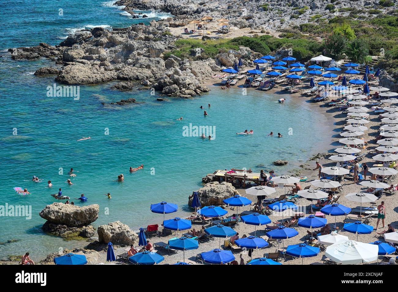 Well frequented beach with many blue parasols and swimmers in the ...