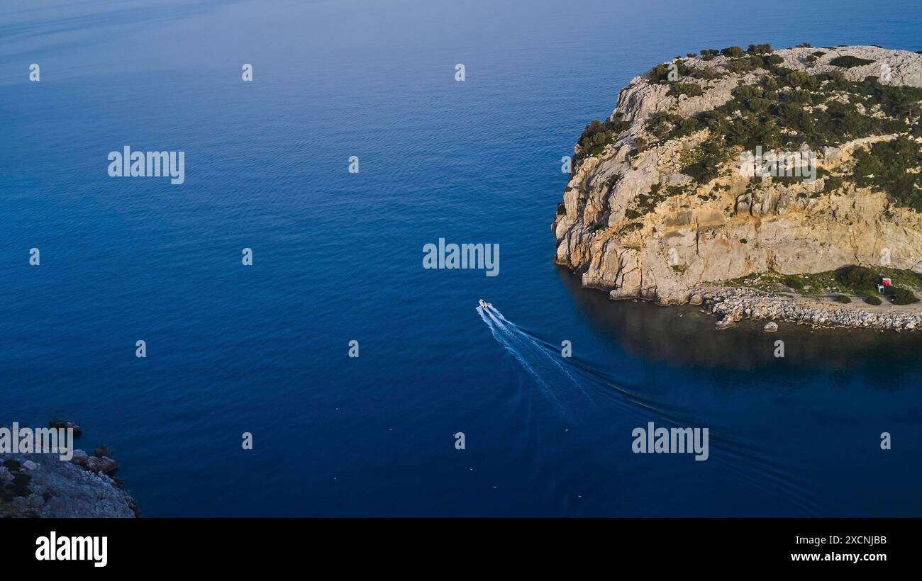Drone shot, Small boat navigating through the clear blue water along a ...