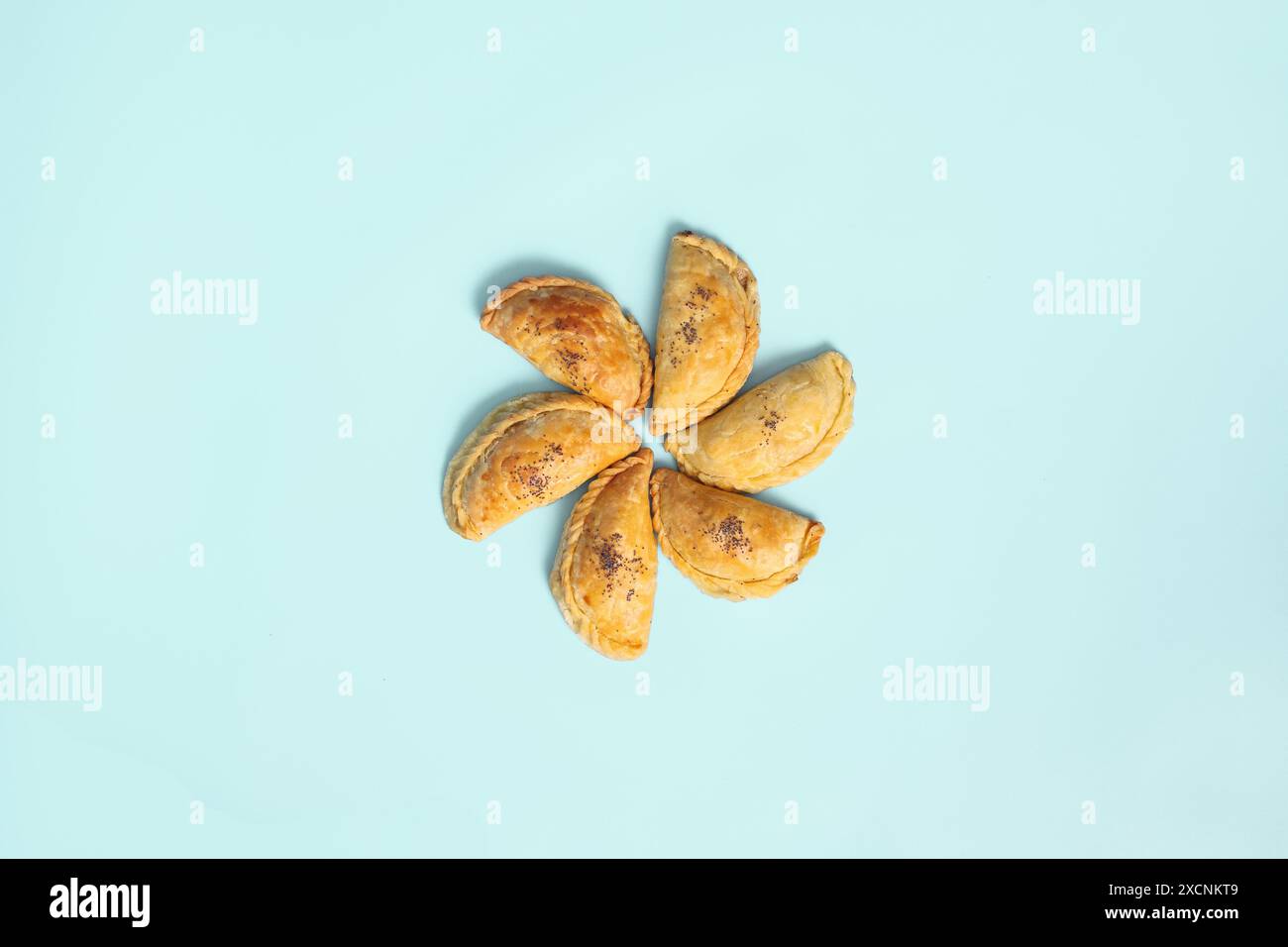 Top view baked samsa pies with meat sprinkled with poppy seeds on blue ...