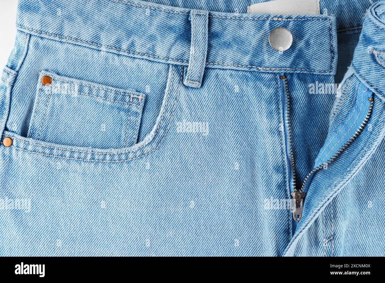 The open zipper, front pocket and metal button of blue denim jeans ...