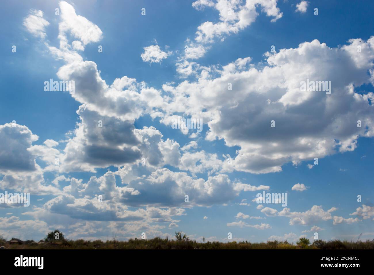 A natural landscape with azure sky, fluffy cumulus clouds, and the sun ...