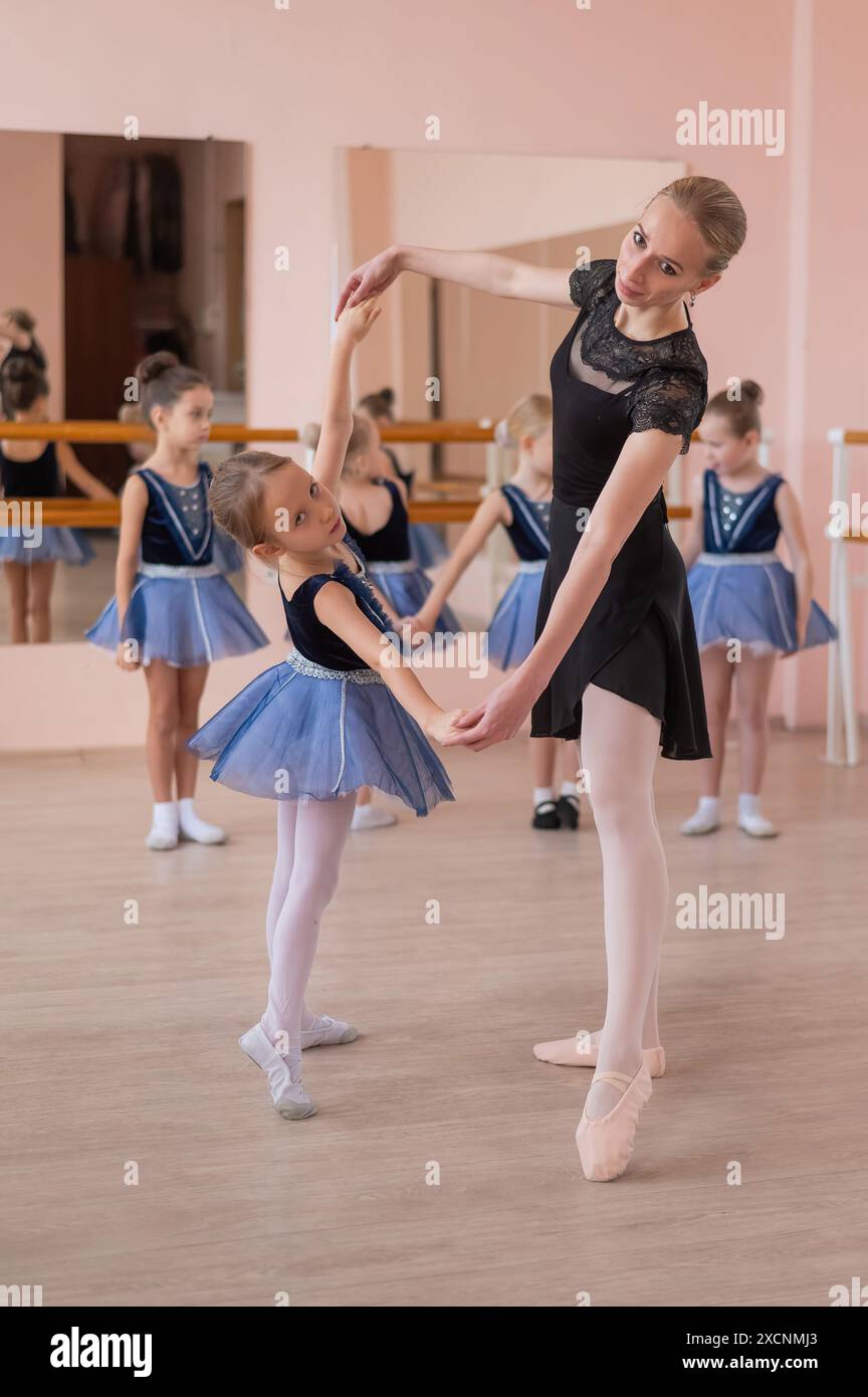 Children's ballet school. Caucasian woman teaching ballet to little ...