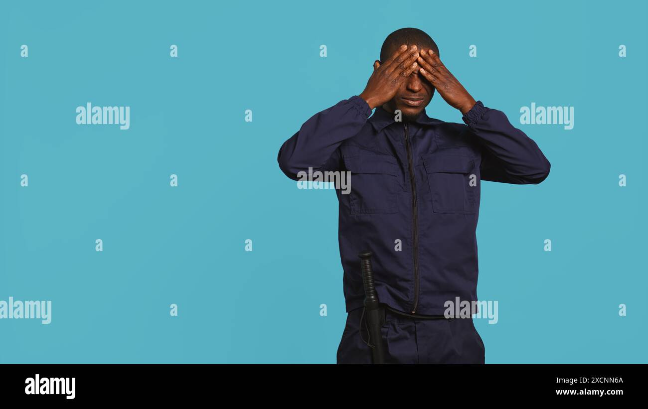 Portrait of tired security guard suffering from painful headache while ...