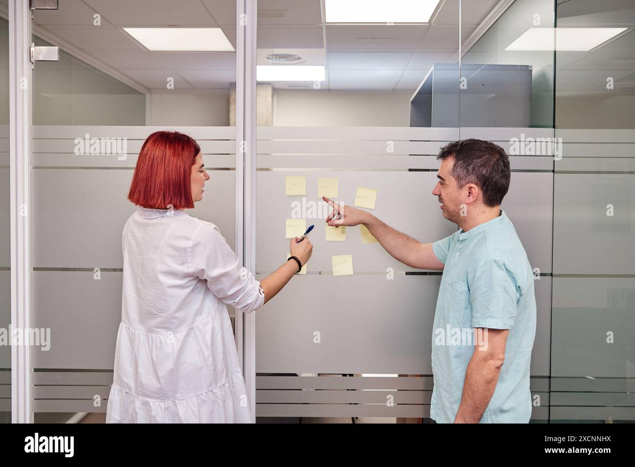 team discussing ideas on sticky notes on windows to plan a marketing ...
