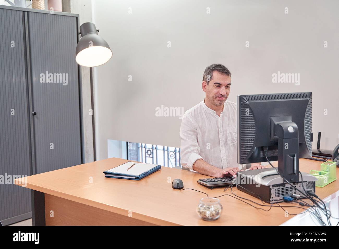 portrait of a man sitting at an office desk working at a computer ...
