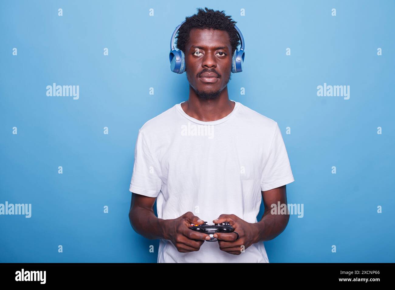 Black man uses headphones and wireless controller while staring at ...