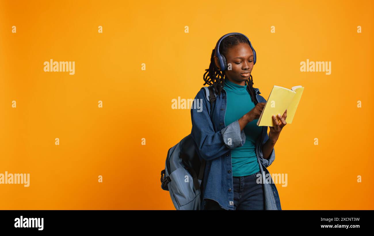 Young girl wearing headphones reading interesting book, enjoying hobby ...