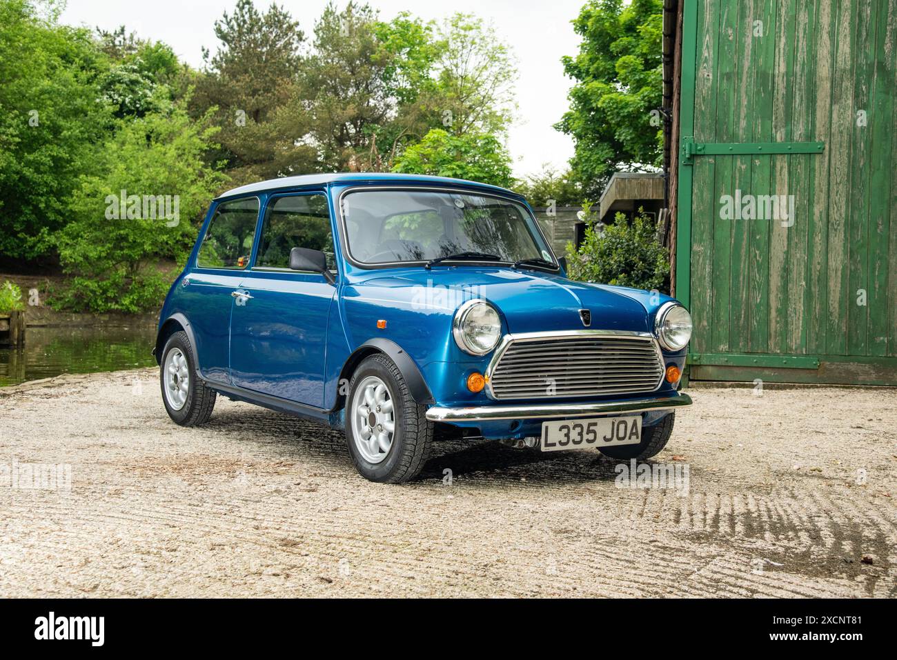 classic Austin Mini parked on a gravel drive in front of an old garage ...