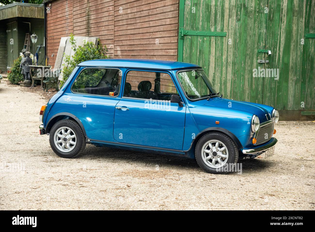 classic Austin Mini parked on a gravel drive in front of an old garage ...
