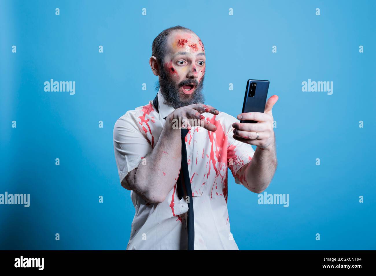 Actor dressed as horror movie brainless zombie taking smartphone ...