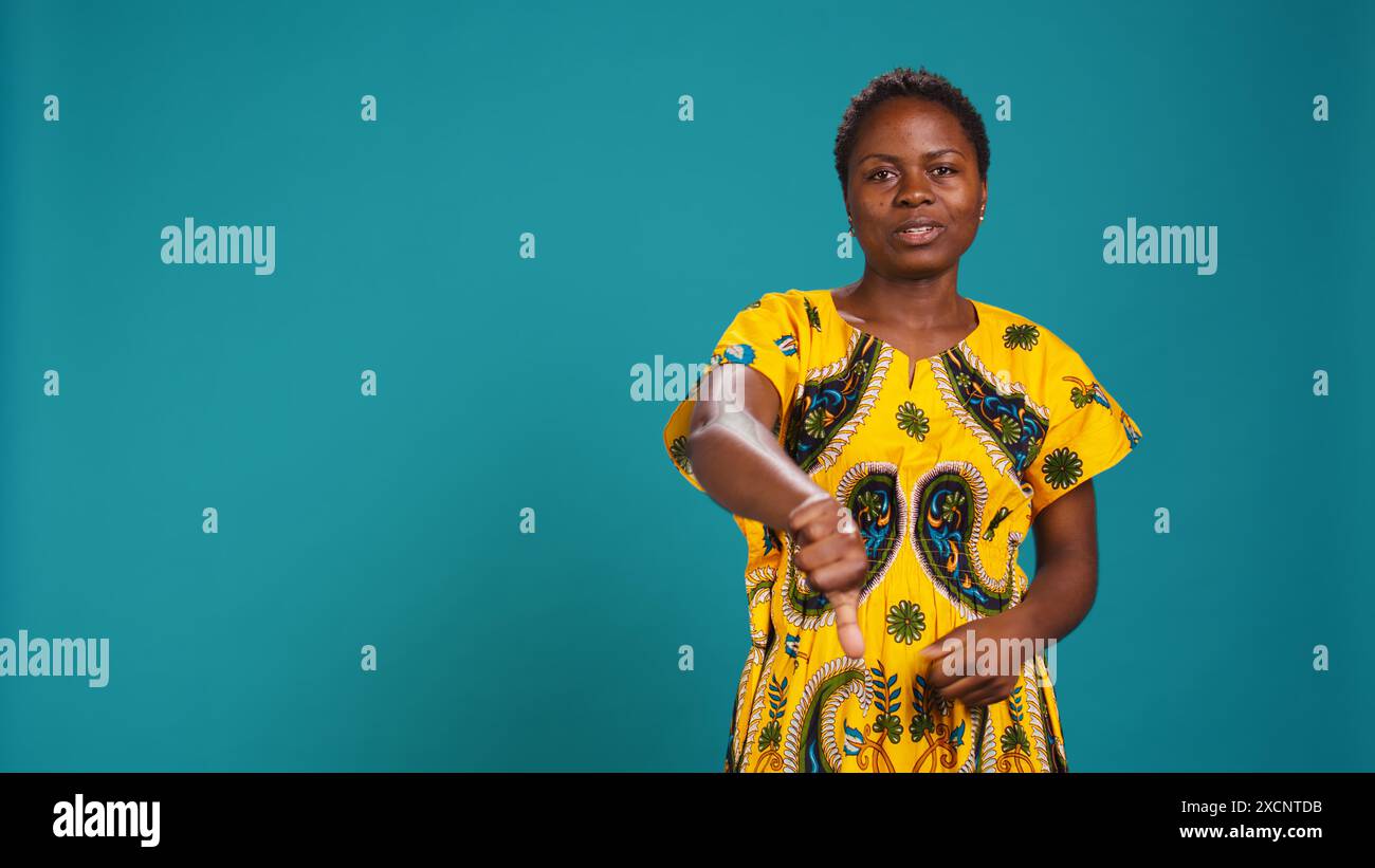 Displeased young woman giving thumbs down in studio, showing her ...