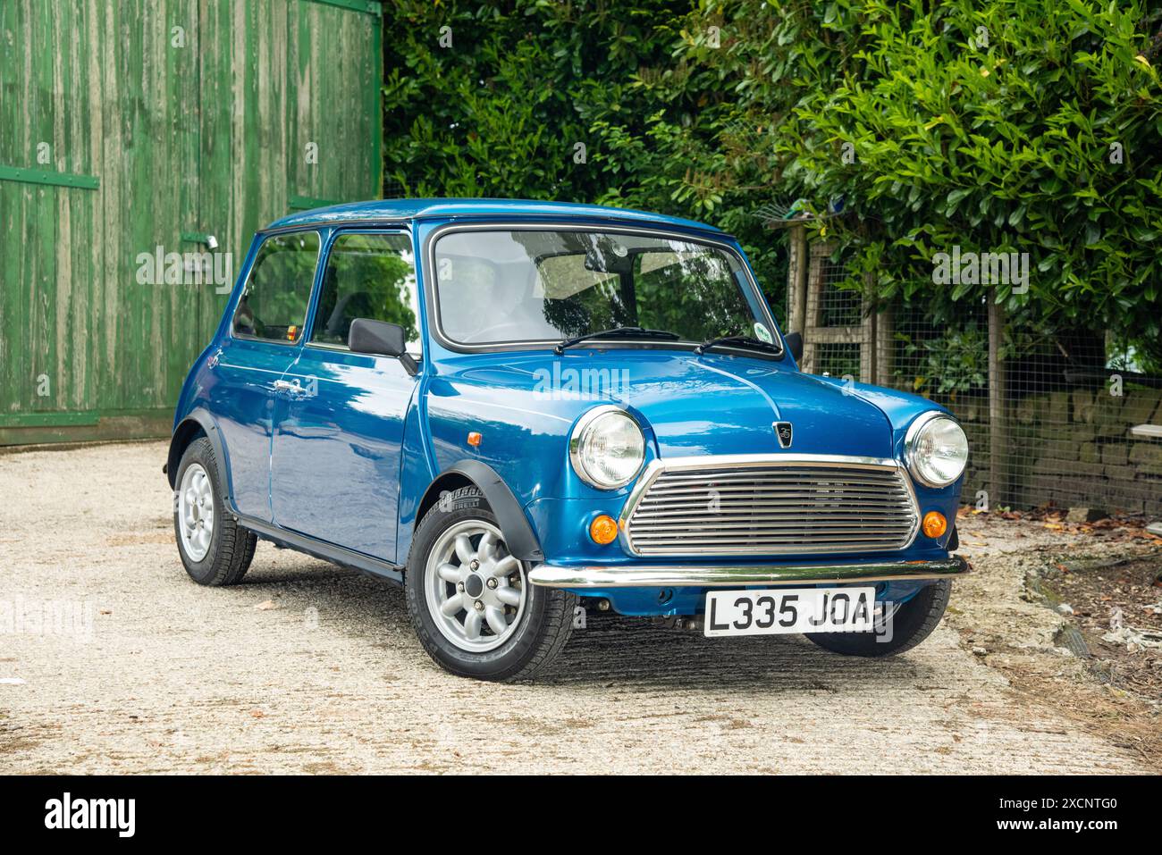 classic Austin Mini parked on a gravel drive in front of an old garage ...