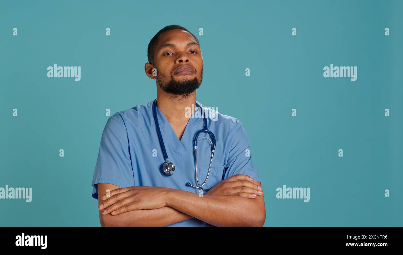Portrait of serious professional male nurse standing with arms folded ...