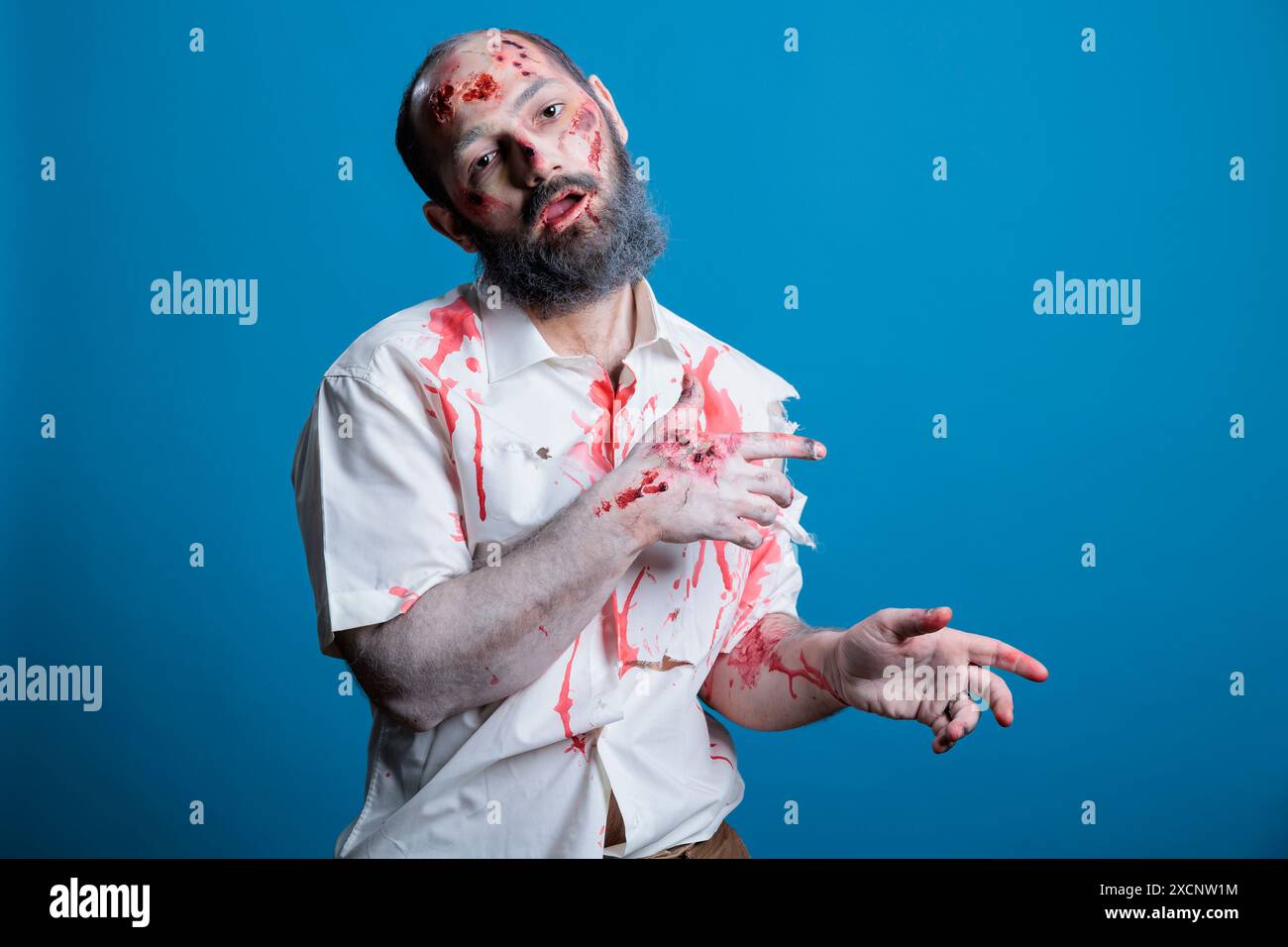 Portrait of brainless infected bloody zombie isolated over blue studio ...