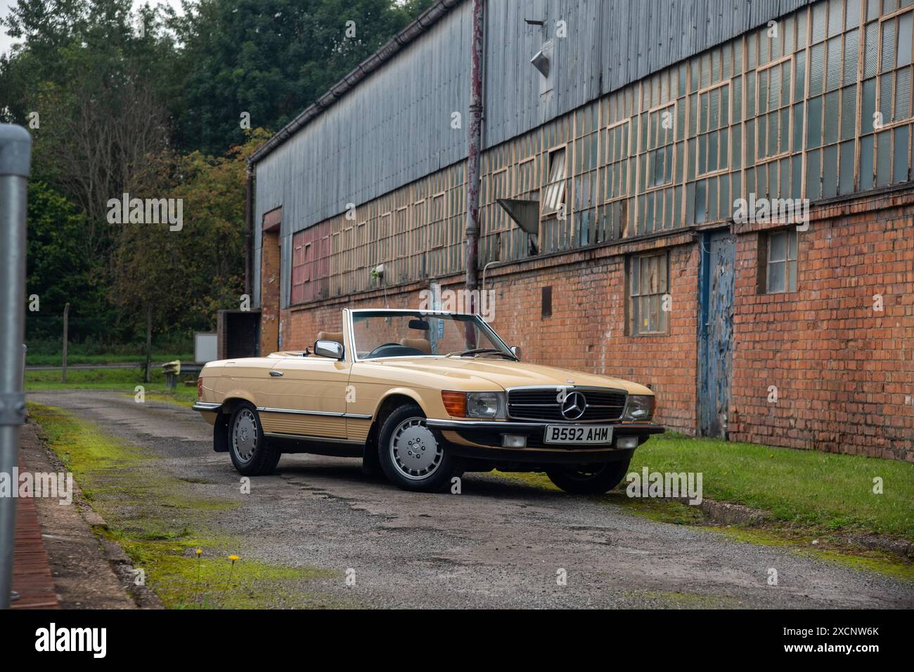 Yellow Mercedes Benz 450SL convertible parked on a lane by an old ...