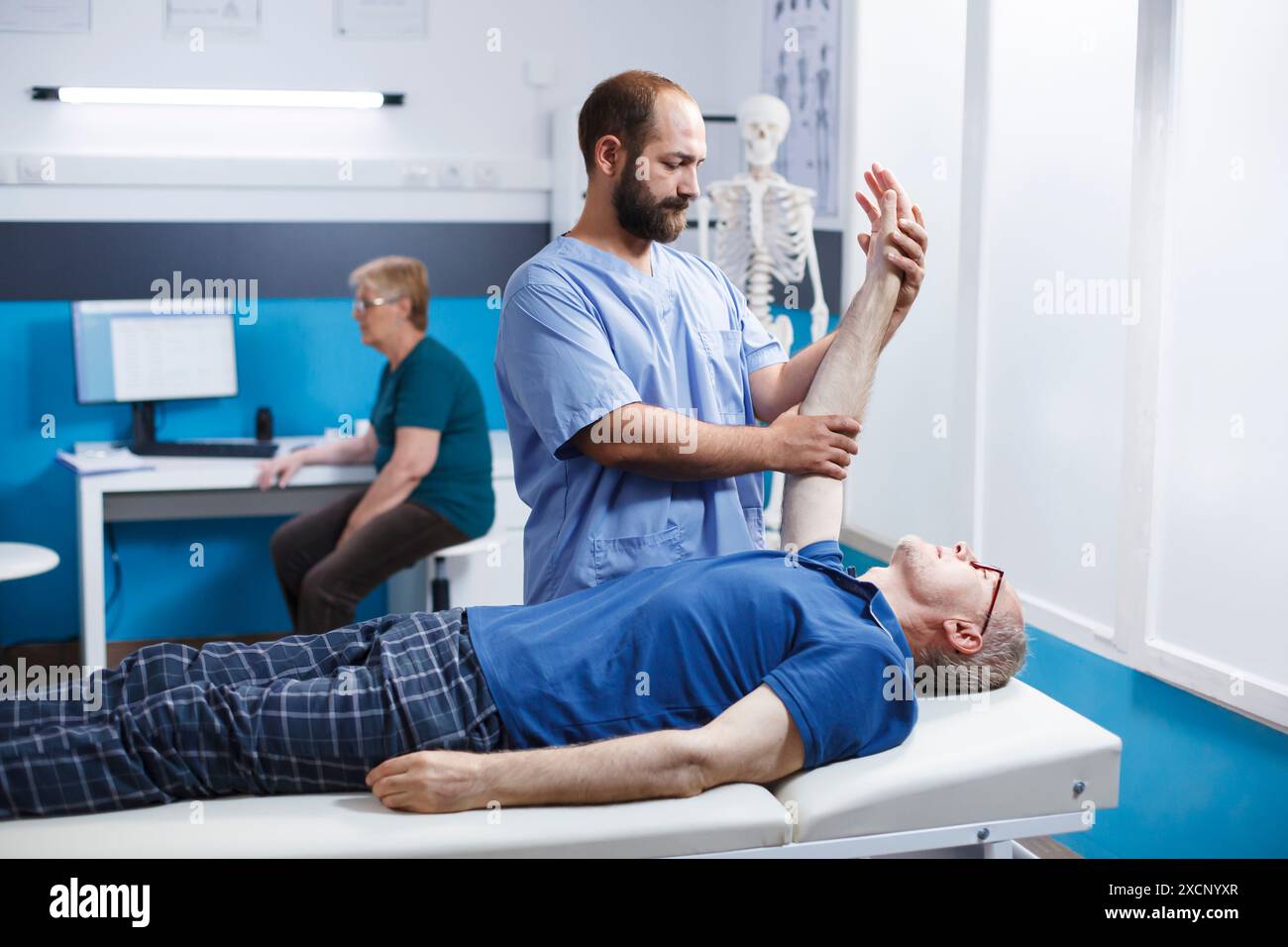 Chiropractor in blue scrubs uses osteopathic massage to help elderly ...