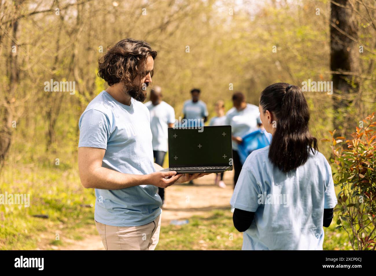Team of ecology volunteers using pc with greenscreen in the woods ...
