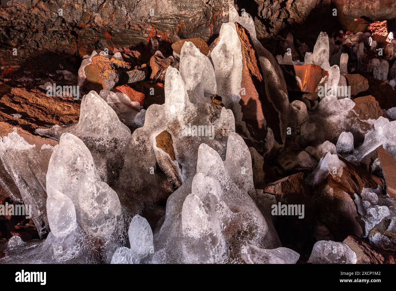 Ice stalagmites (icicles) formed on the red iron volcanic rock surface ...