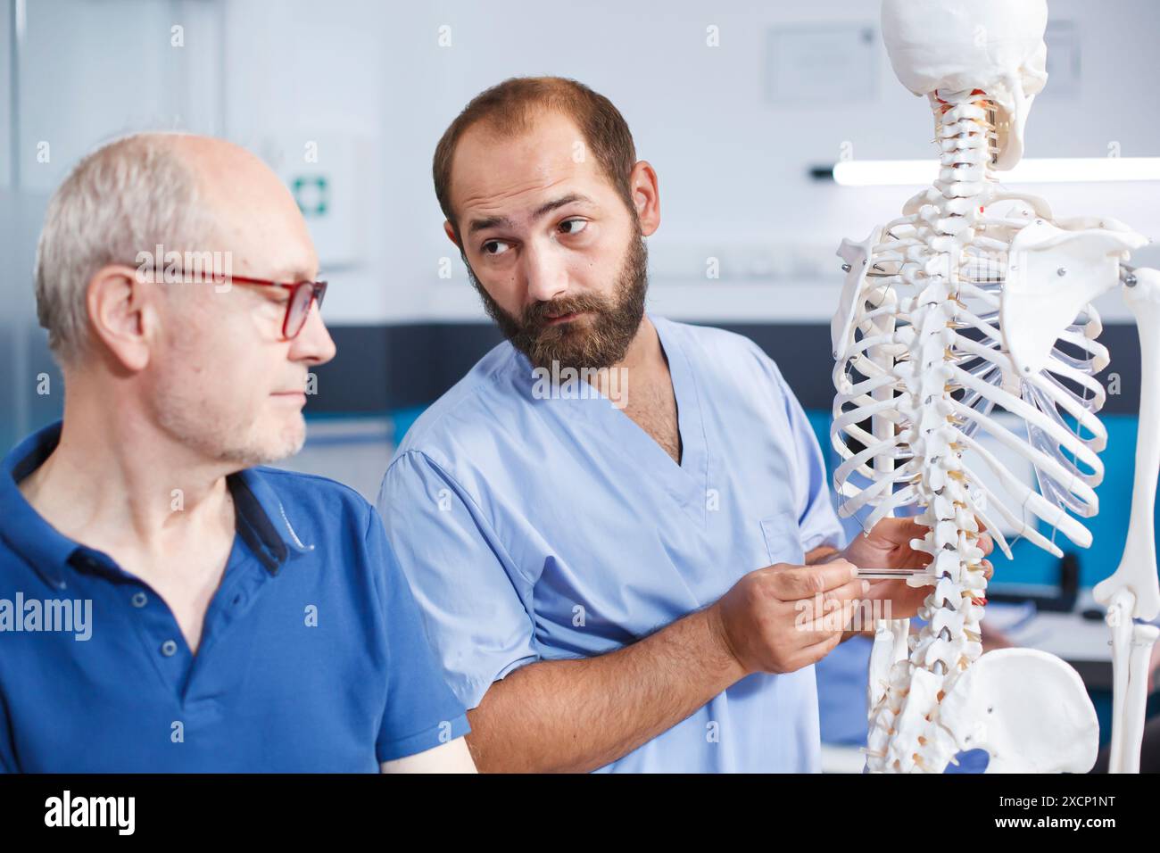 Chiropractor shows spinal cord bones to senior man for orthopedic ...