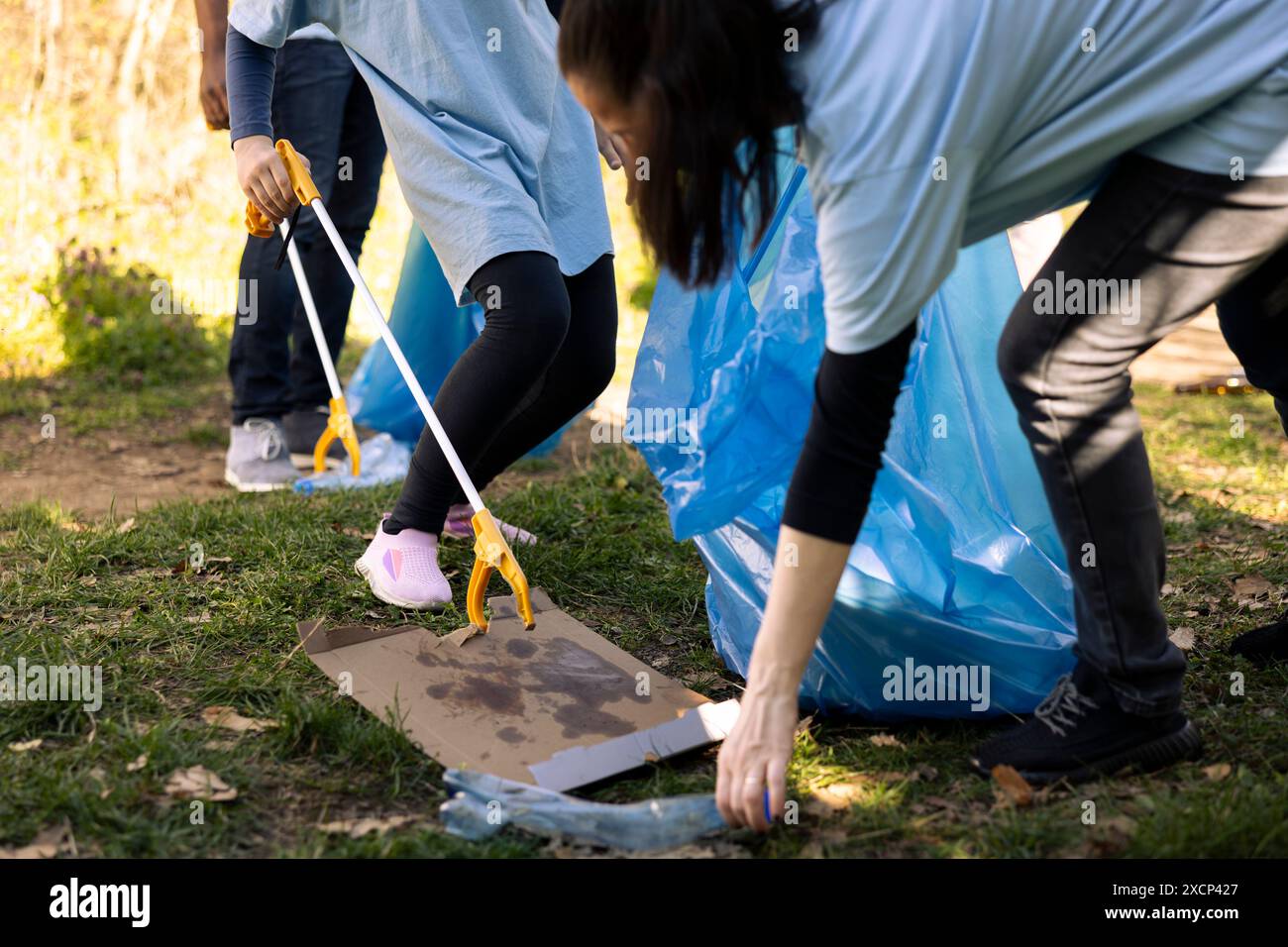 Child and woman grabbing junk and plastic from the ground, recycling in ...