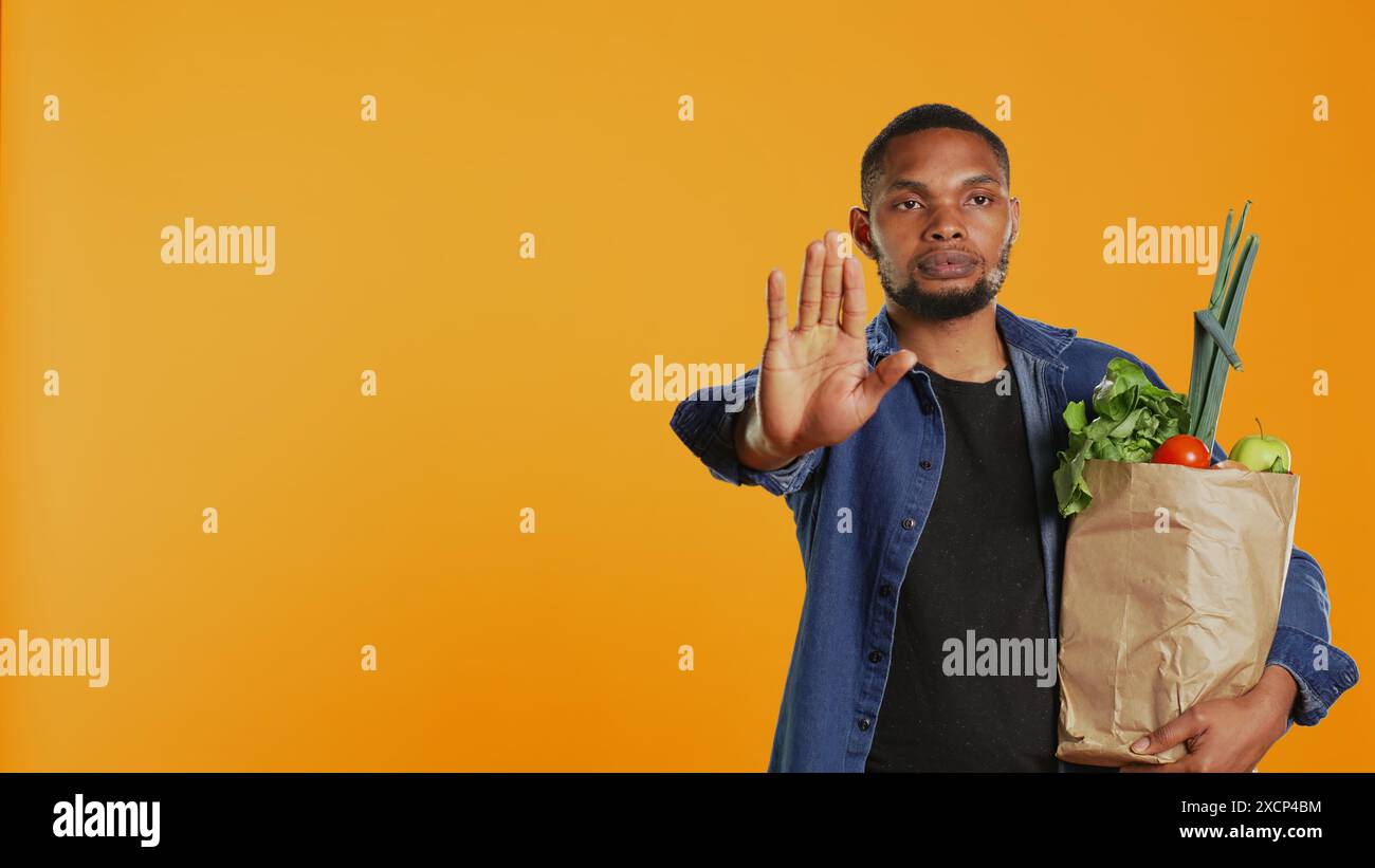 Vegan person showing a stop sign with his palm while he carries a bag ...