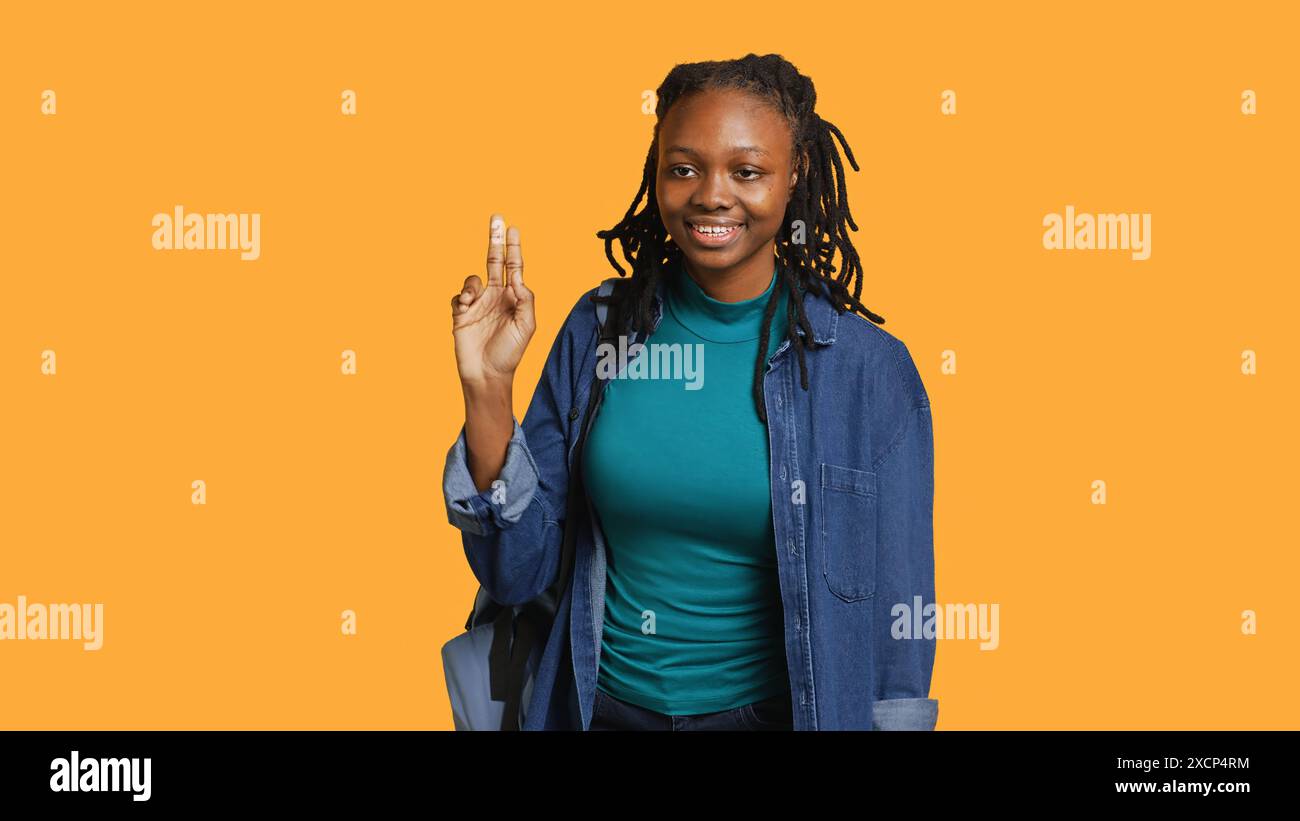 Smiling african american student at school raising arm to answer ...