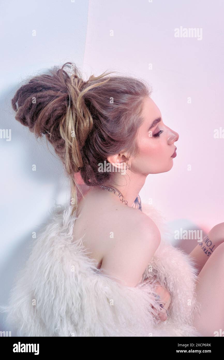 Woman wearing a white fur coat and sporting a messy bun poses for a ...
