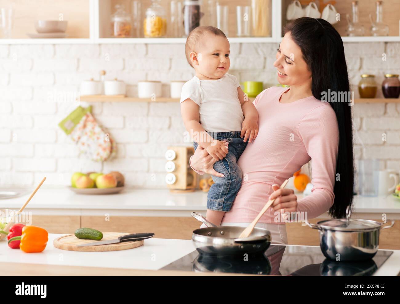 Woman Holding Baby in Kitchen, Cooking Together Stock Photo - Alamy