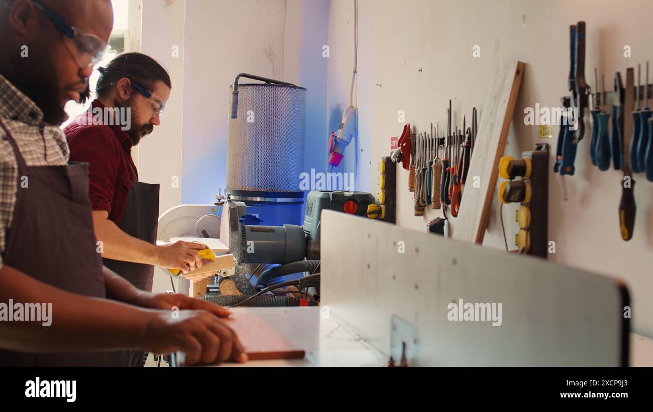 Team of woodworkers in assembly shop using sandpaper and spindle ...